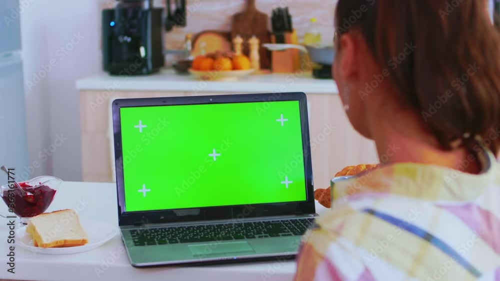 Working on tablet pc with green screen in kitchen during breakfast ...