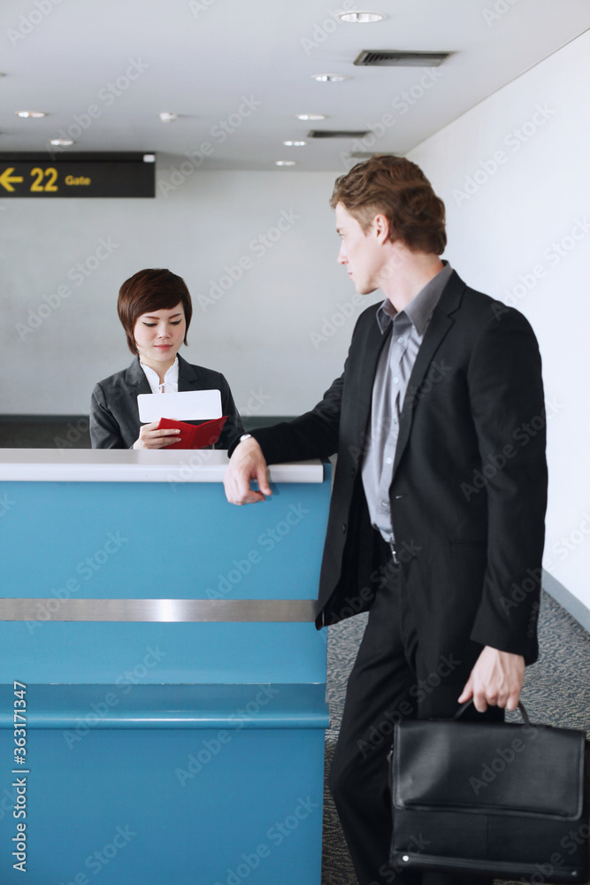 Airline check-in attendant checking businessman's passport at the ...