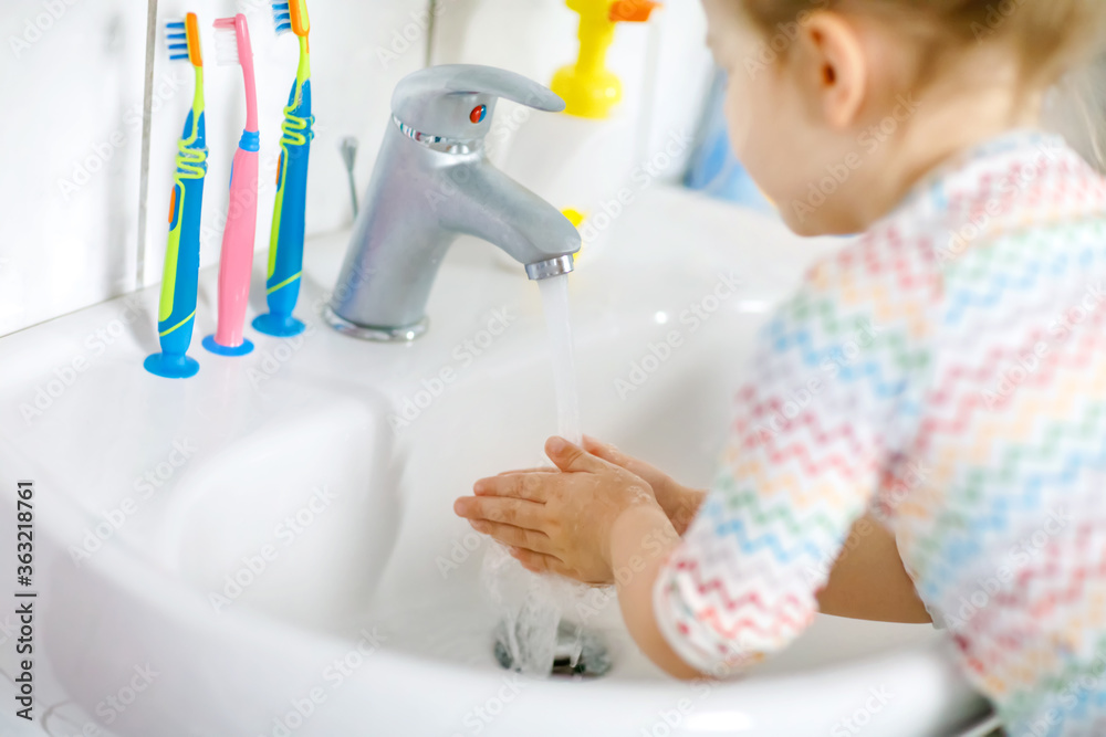 Closeup of little toddler girl washing hands with soap and water in ...