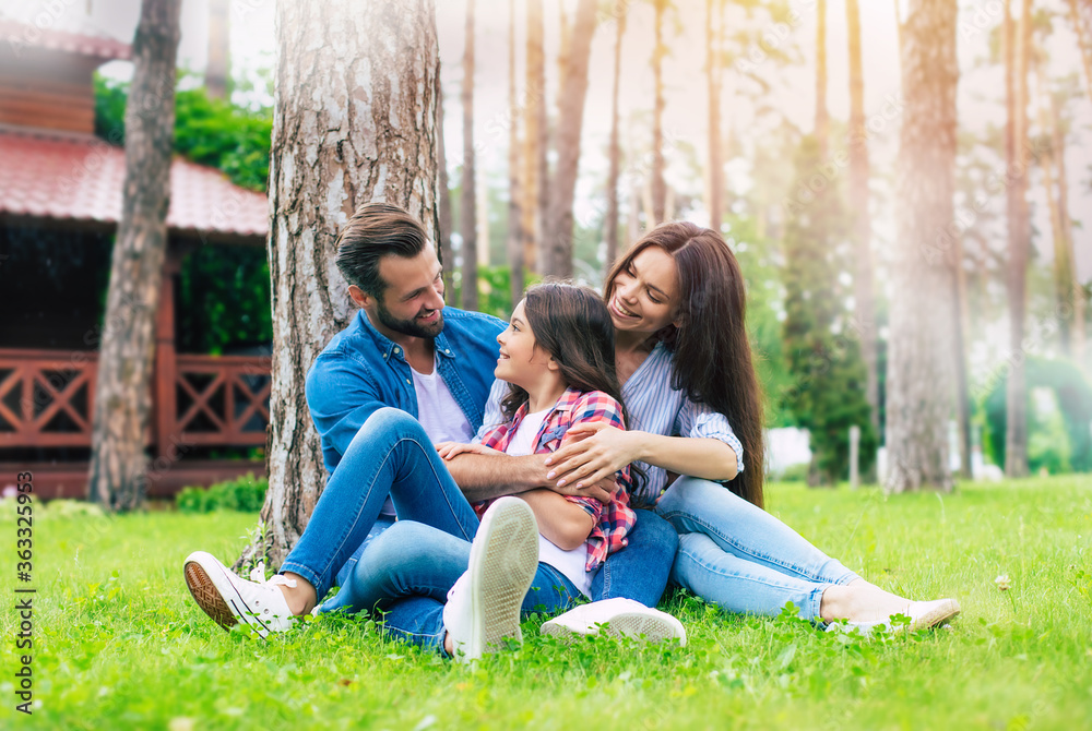 Beautiful happy family while sitting together on the grass and hugging ...