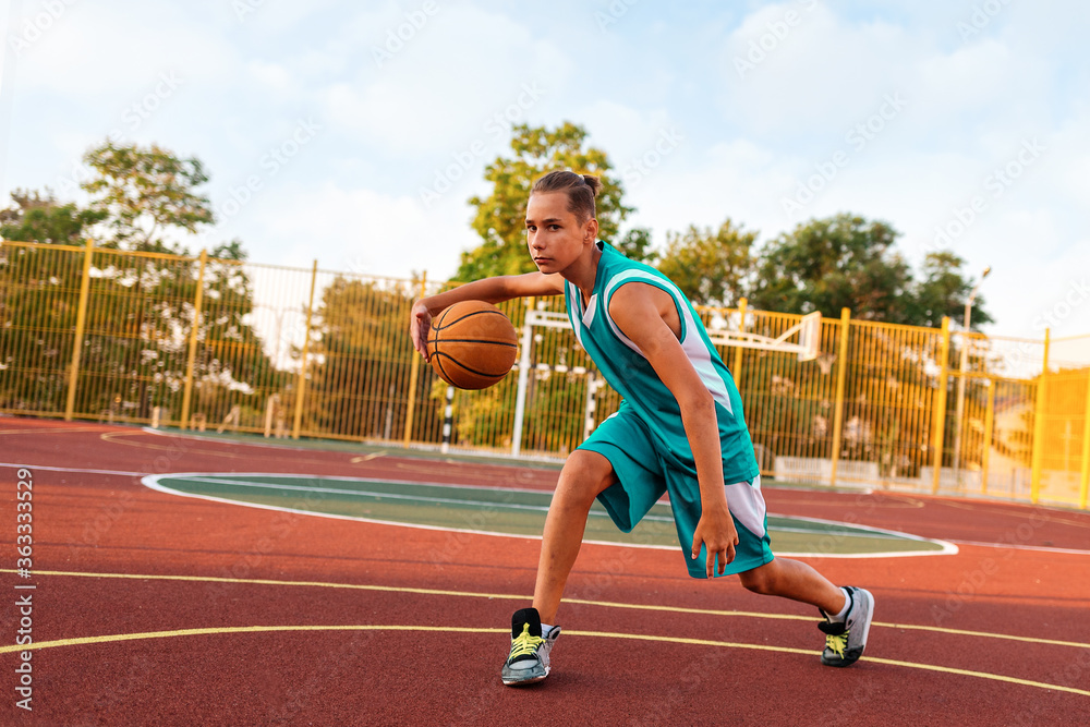 Basketball. A teenage boy in green sportswear plays a basketball. In ...