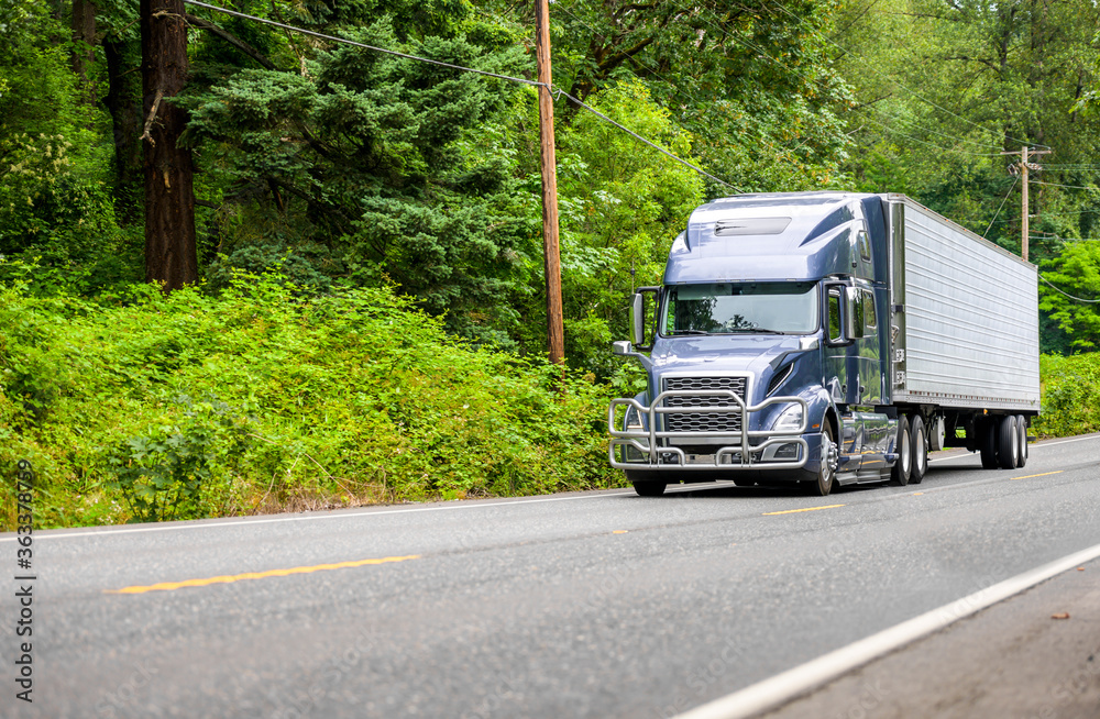 Gray big rig diesel semi truck with grille guard transporting cargo in ...