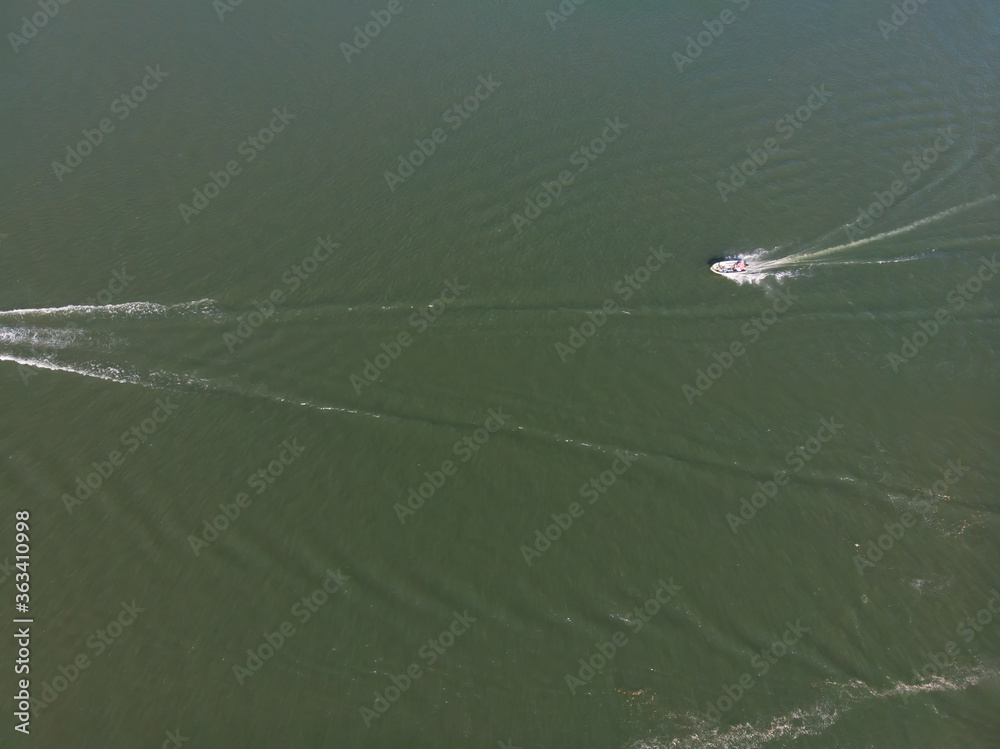 The boat is floating at speed on the water with a spot, top view with ...