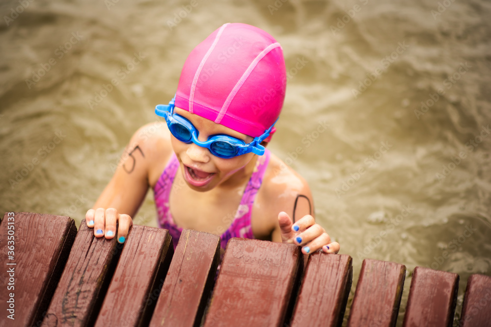 Young small 9 years old girl swimmer on finish line after open water ...
