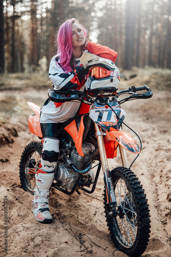 Beautiful racer girl with pink hair in motocross kit sitting on her ...