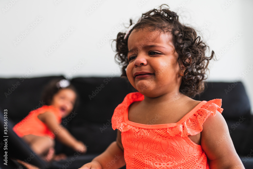 Portrait of a baby girl crying and her sister twin background Stock ...