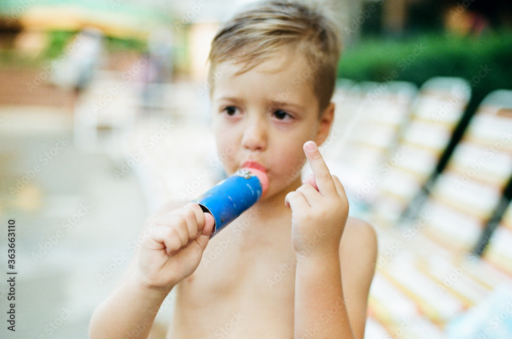 Cute young boy giving the photographer the finger while sucking on a ...
