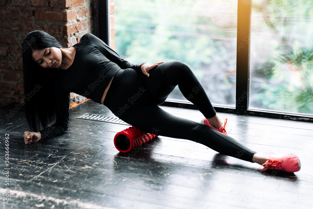 The girl is a Pilates trainer working out a massage roll of the fascia ...