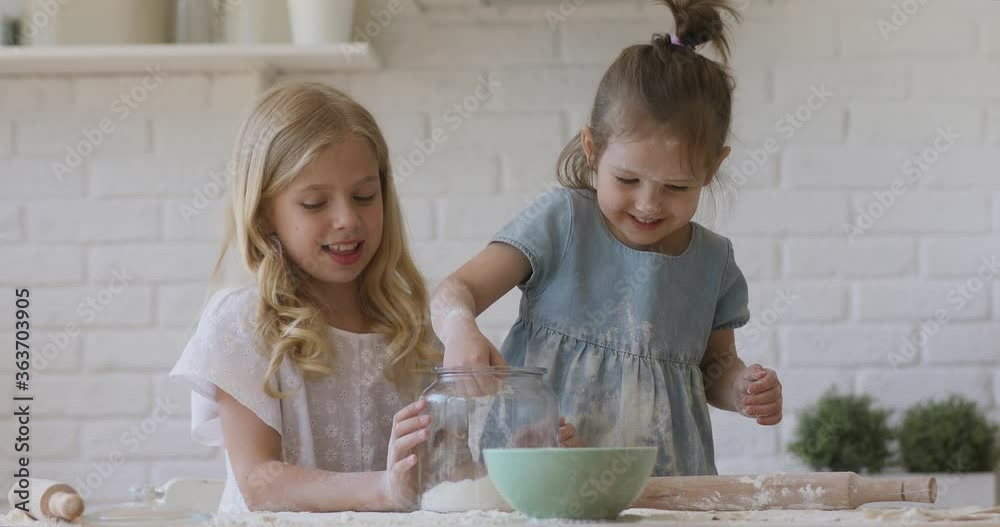 Happy adorable kids sisters enjoy cooking together preparing dough, two ...