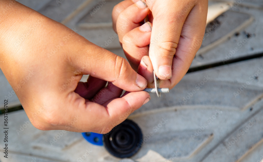 A boy collects parts of a metal constructor in the open air and ...