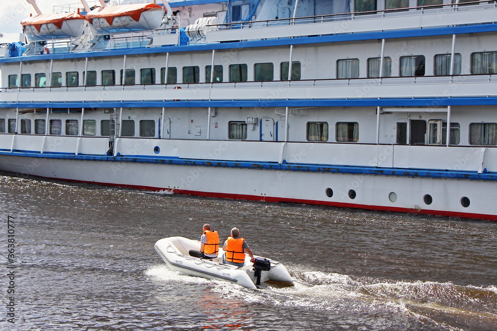 Little PVC inflatable boat with small outboard motor with two people in ...