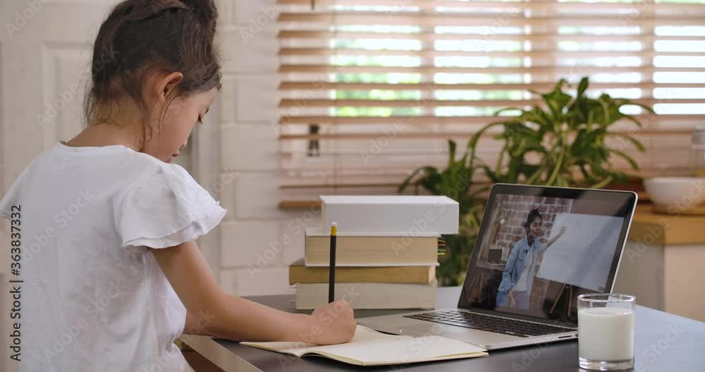 Young asian little girl watching lesson online and studying from home ...