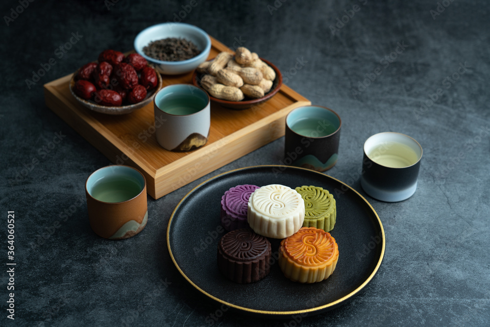 Colorful moon cakes are placed on black plates. Chinese traditional ...