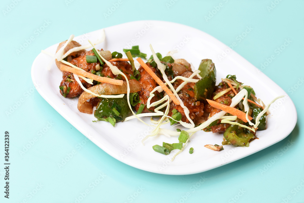 Chilli paneer or Spicy cottage cheese, Garnish with capsicum, onion ...