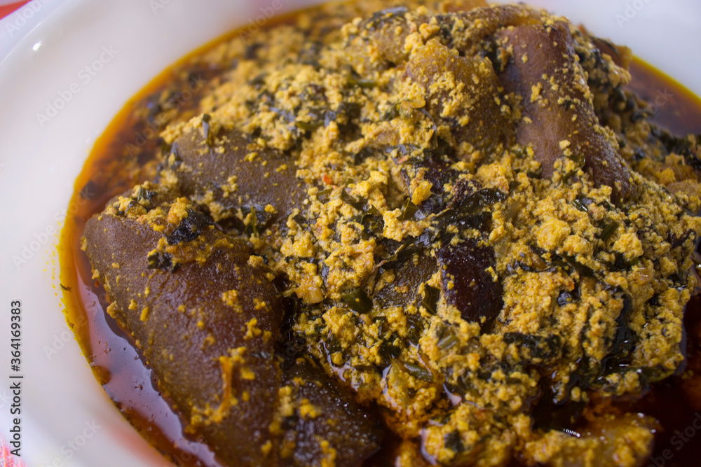 A white bowl of delicious Nigerian Egusi soup cooked with assorted meat ...