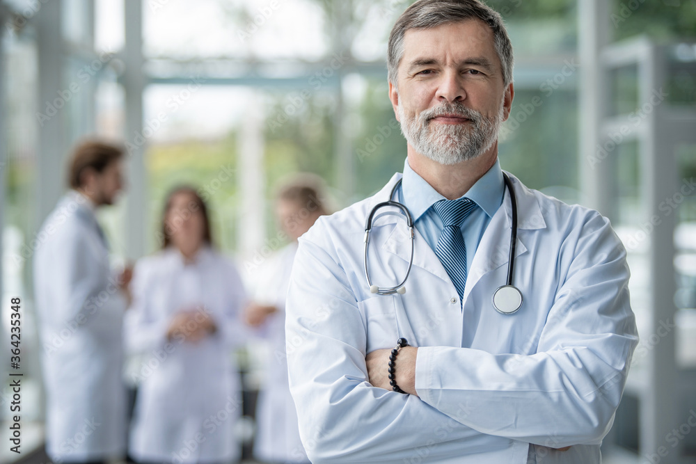 Confident smiling doctor posing in the hospital with medical team ...