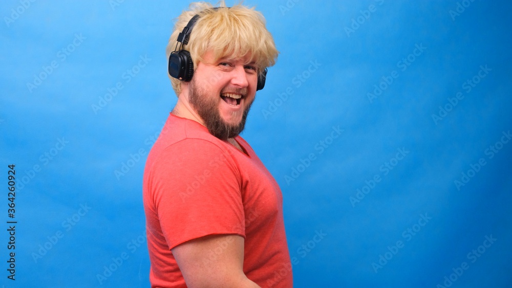 freaky fat man in a wig and a pink T-shirt in his hands listens to ...
