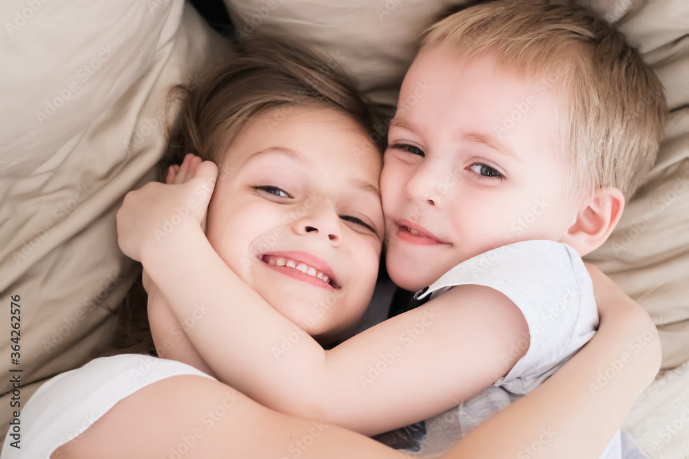 Portrait of pretty and cute little brother and sister hugging together ...