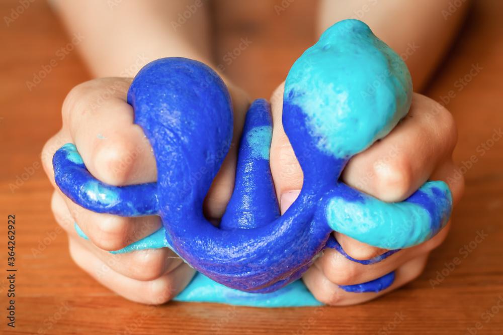 The child plays with a home made light blue toy that is called slime ...