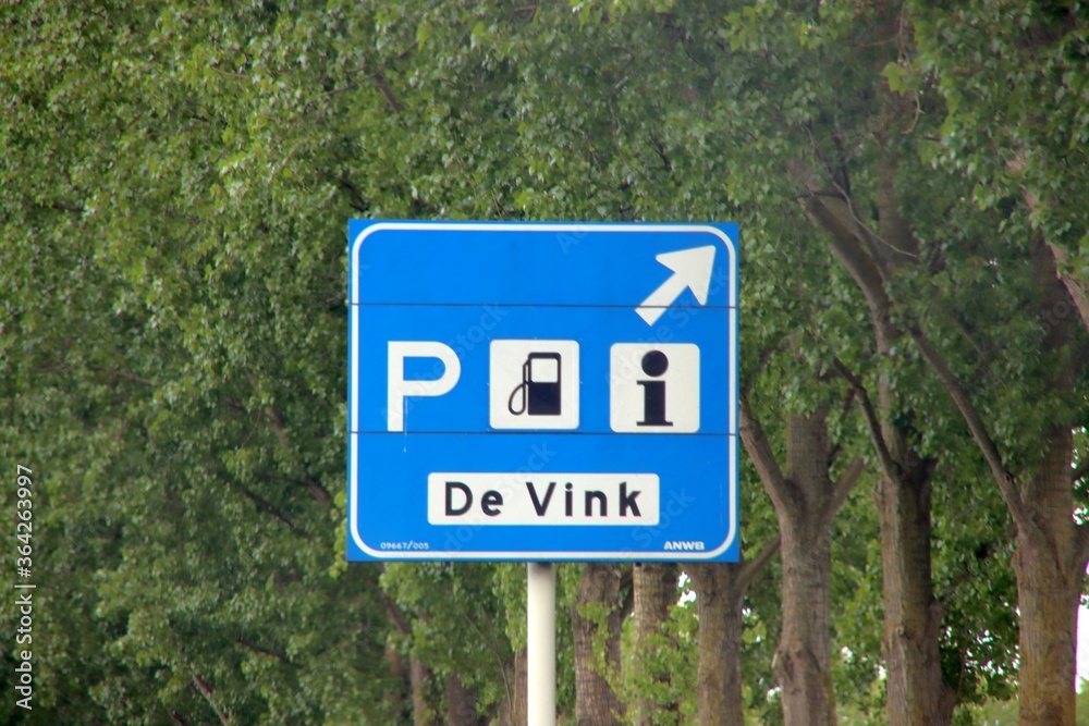Direction sign in blue and white heading parking and petrol station De ...
