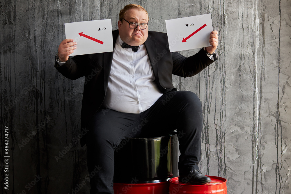 fat caucasian oil businessman is in desperate, unhappy male sits on oil ...