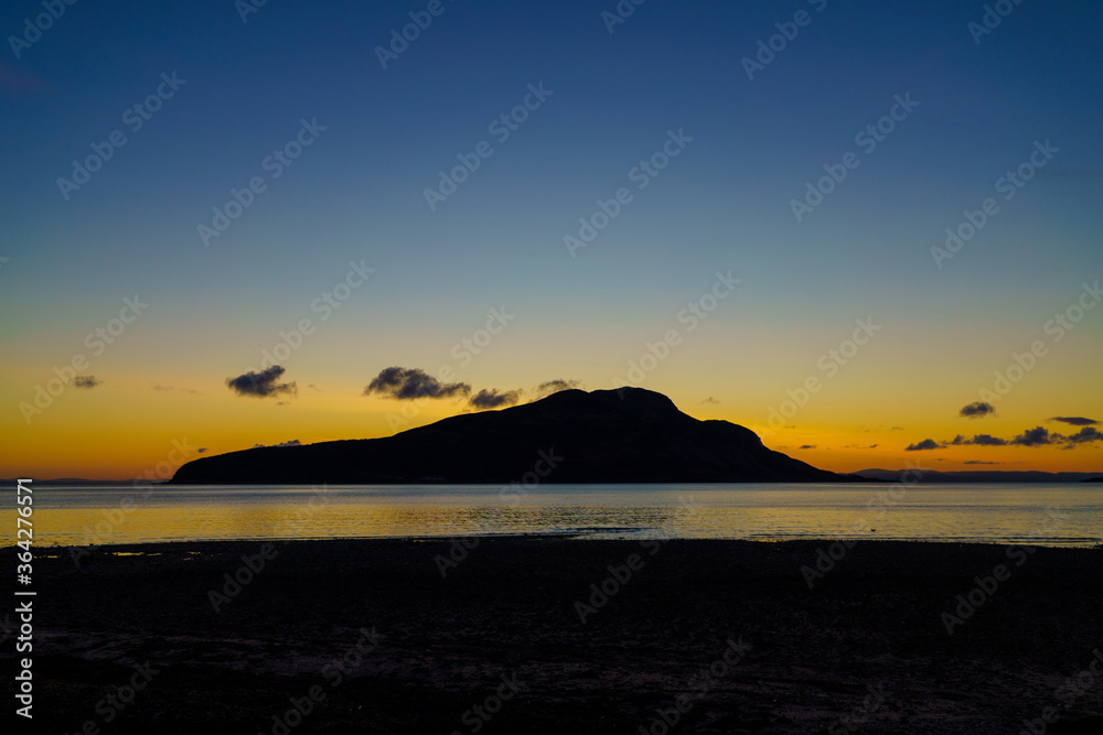 Sunrise over Holy Isle from Lamlash beach on the Isle of Arran in ...