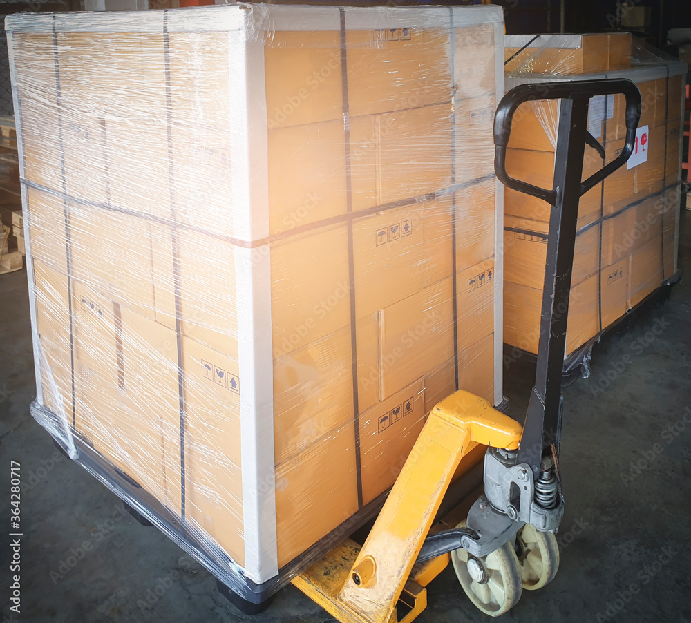 Large shipment boxes stacked on pallet and Yellow hand pallet truck ...