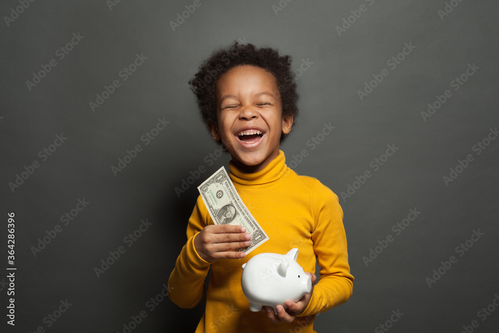 Smart happy black child boy putting in piggy bank one dollars banknote ...