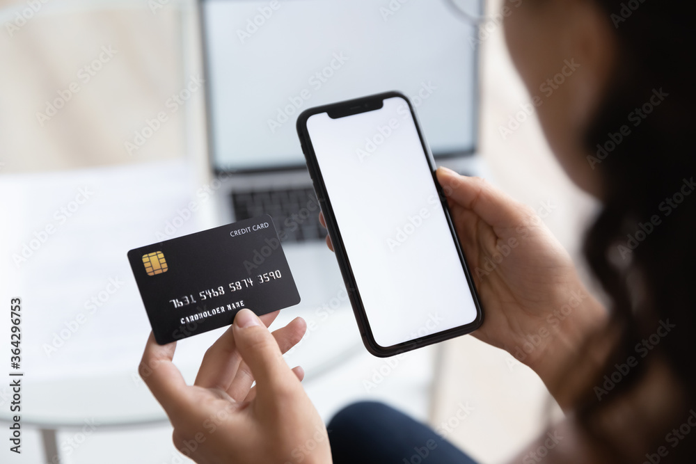 Close up over shoulder view of woman hold smartphone and credit card ...