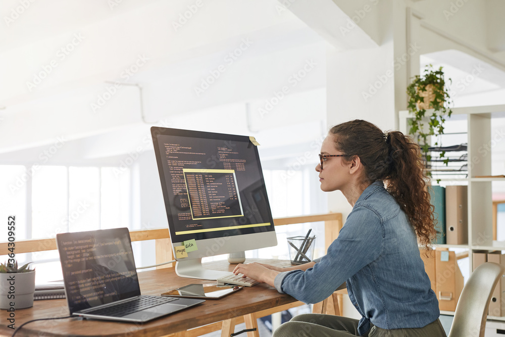 Side view portrait of female IT developer typing on keyboard with black ...