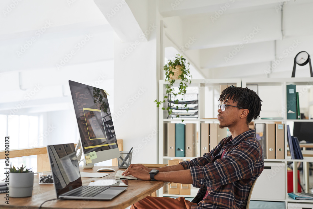 Side view portrait of African-American IT developer typing on keyboard ...