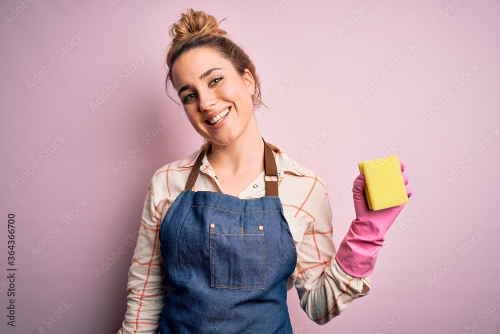 Beautiful blonde cleaner woman doing housework wearing arpon and gloves ...