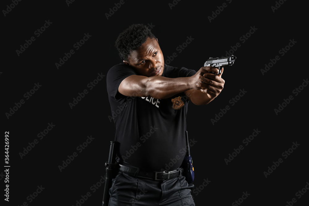 Aggressive African-American police officer with gun on dark background ...