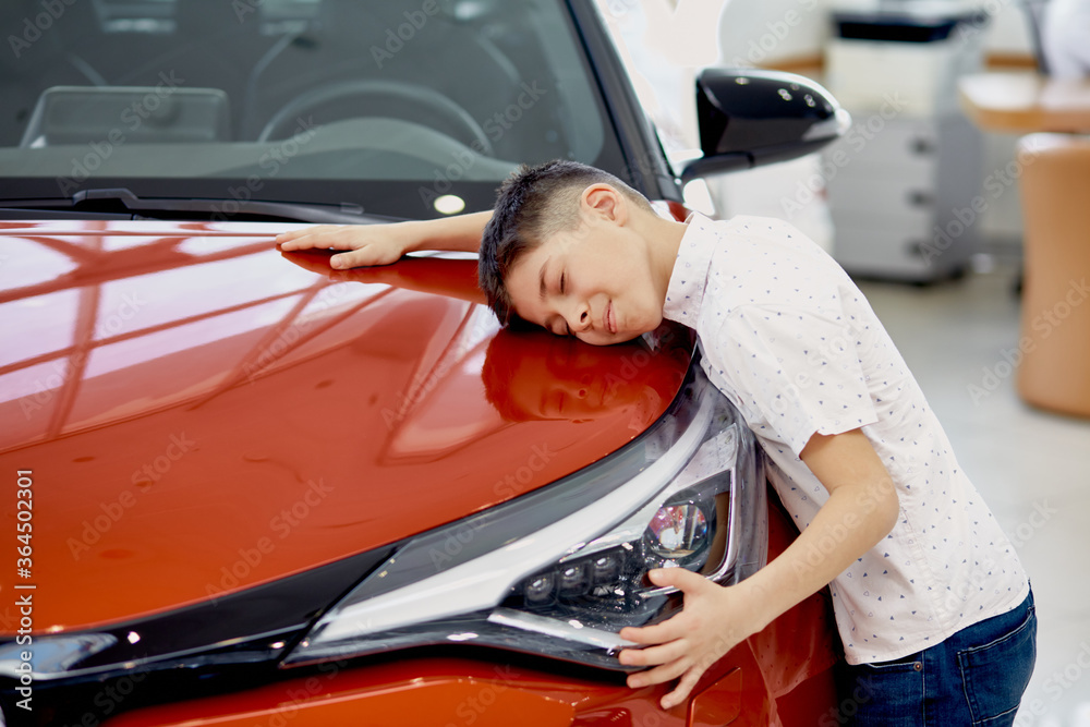 cute caucasian child boy hug new car in dealership, he wants parents to ...