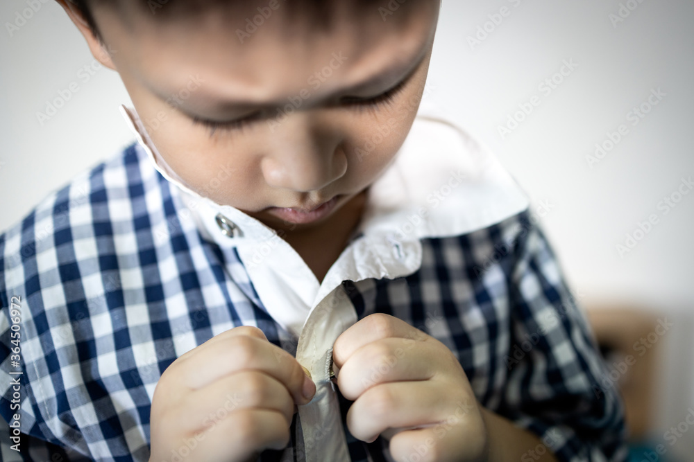 Little child is trying to wear shirt,student button or unbutton his ...