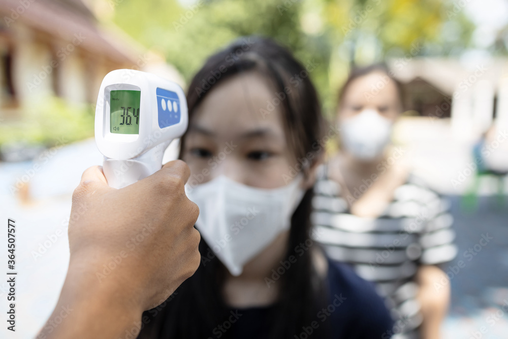 Asian student girl wear medical face mask is checking fever outside of ...