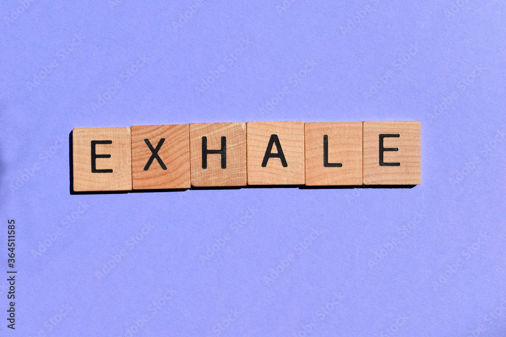 Exhale, single word in wooden alphabet letters isolted on purple ...
