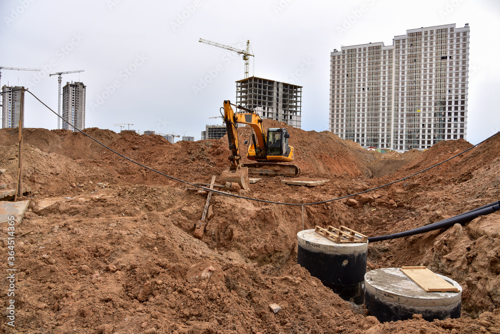 Excavators on earthworks at construction site. Backhoe digs a pit for ...