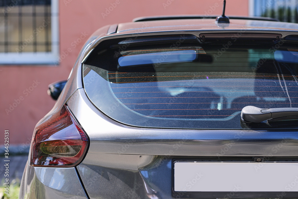 Back window of grey car parked on the street in summer sunny day, rear ...