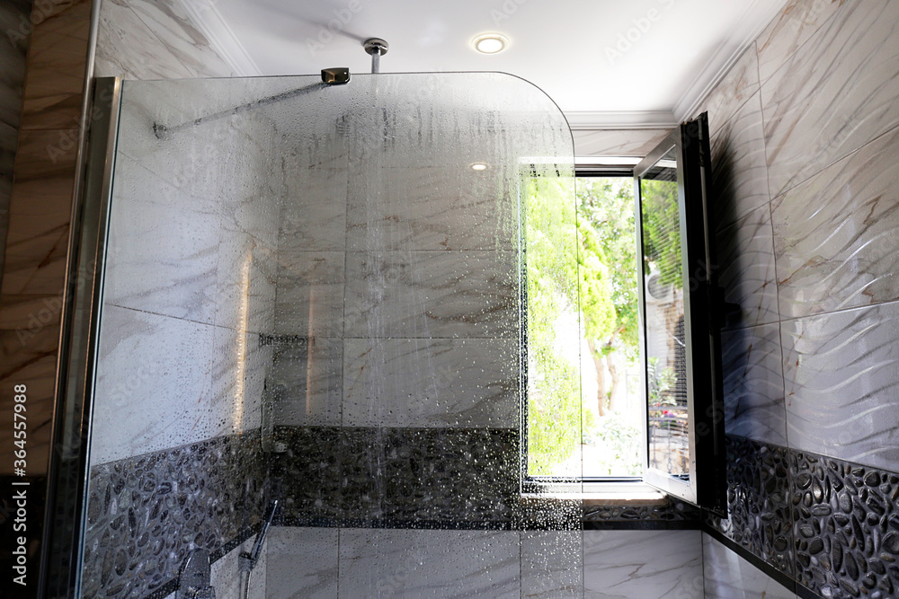 Bathroom filled with natural light through an open window. Shower head ...