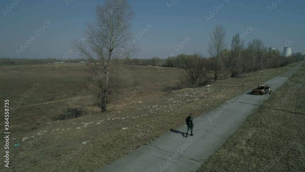 Vidéo Stock Burned out wrecked car. The soldier walks along a road ...
