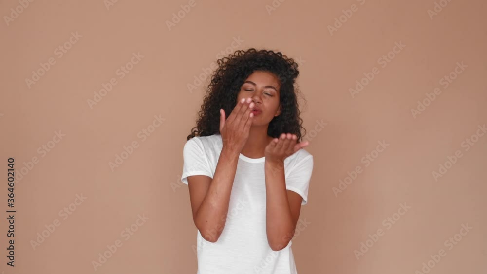 beautiful black woman blows a smooch kiss isolated over brown studio ...