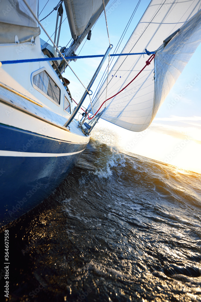 White sailboat in an open sea at sunset. Single handed sailing a 34 ft ...