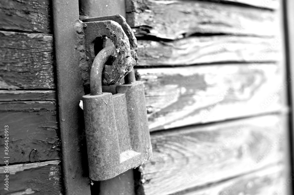 A black and white photograph of an old rusted lock sees on a wooden ...