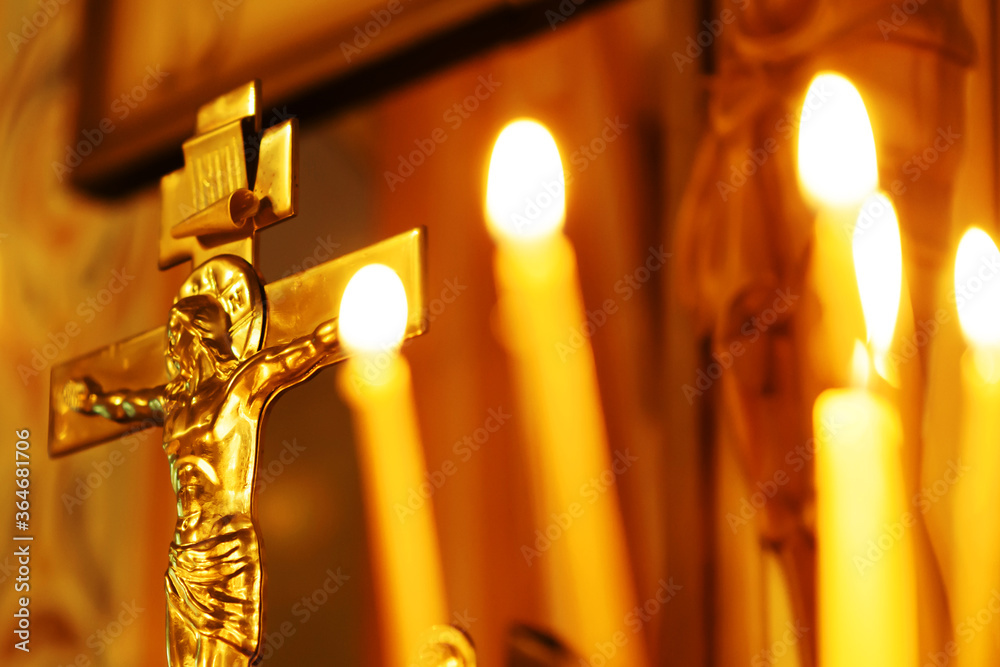 Burning candles in the temple on the background of a golden cross ...