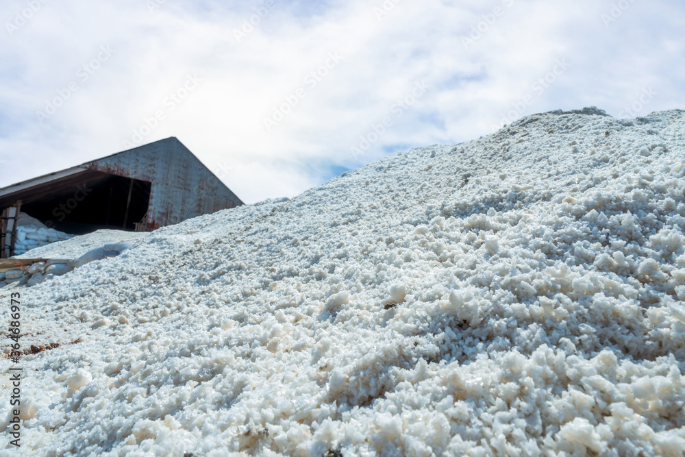 Brine salt farm warehouse with sky and clouds. Pile of organic sea salt ...