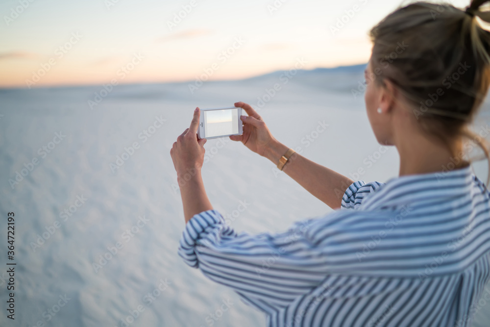 Back view of female holding smartphone making picture of beautiful ...