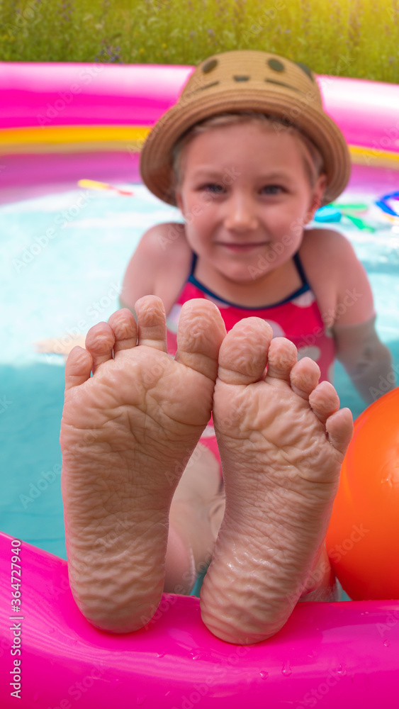 Kids feet laying on colorful rainbow inflatable swimming pool. Young ...