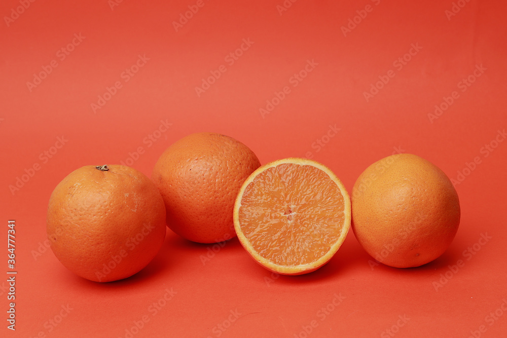 bodegón de naranjas enteras y una media naranja jugosa sobre fondo liso ...