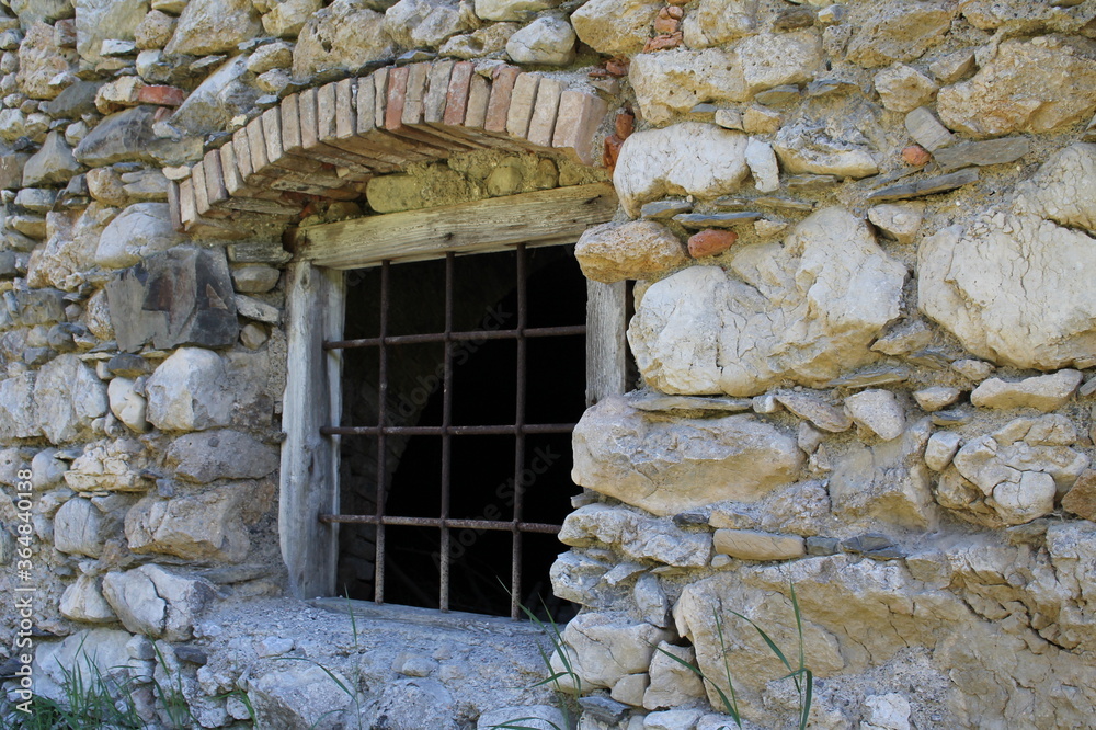 Window with railing in an old stone wall, dark interior, brick arch ...